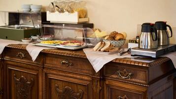Buffet com diversos alimentos, incluindo pão, doces e um espaço para café.