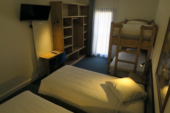 Quarto com duas camas, televisão fixada na parede, guarda-roupa de madeira e cama beliche.