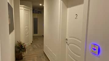 Um corredor com piso de madeira, paredes brancas e portas numeradas 2 e 3.