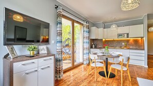 Uma cozinha moderna com área de jantar, piso de madeira e uma janela grande com cortinas.