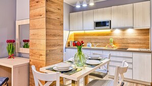 Cozinha moderna com armários de madeira, micro-ondas e área de jantar com mesa posta para dois.