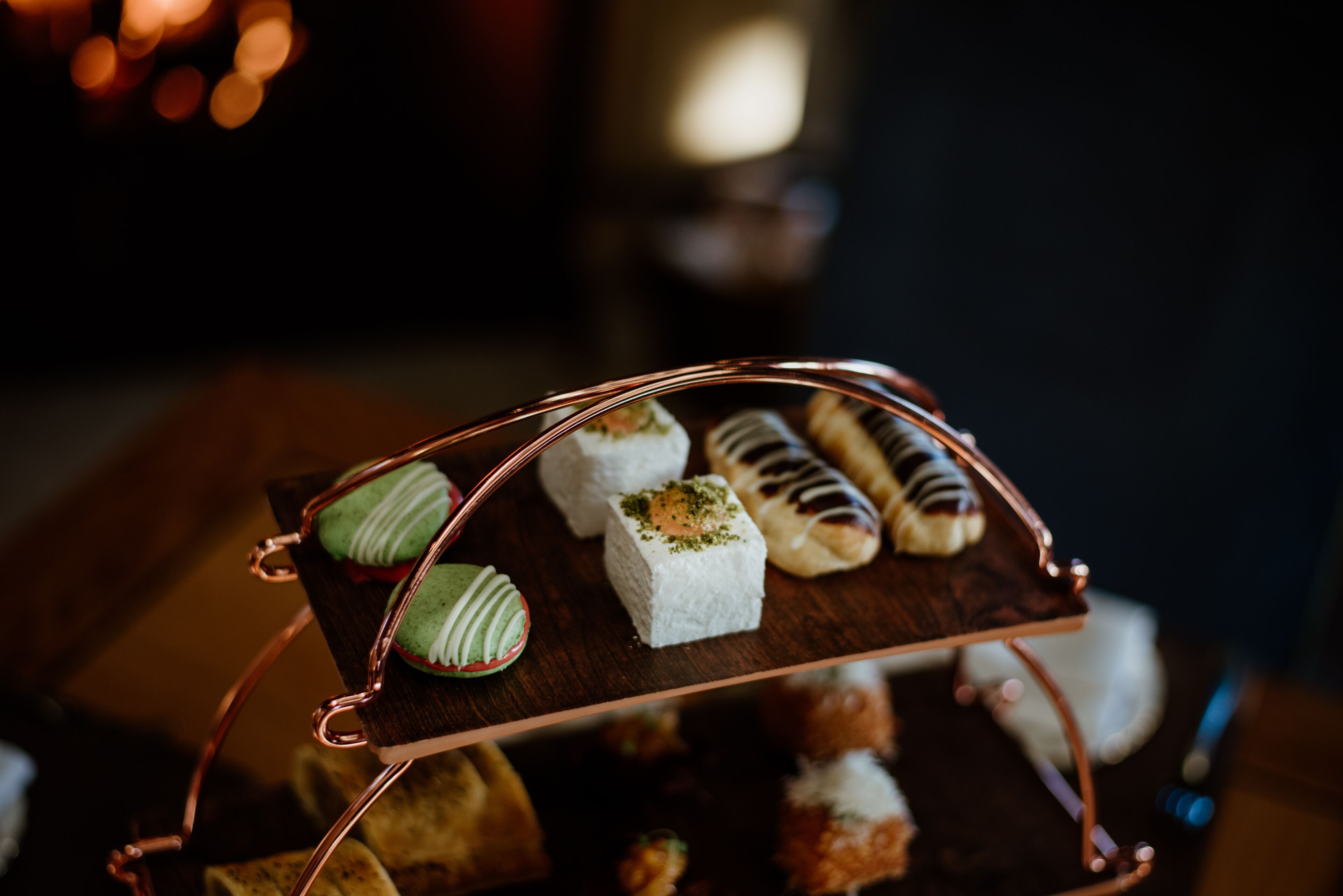 Uma mesa de sobremesas com diversos doces em um suporte de cobre.
