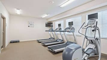 Sala de ginástica com esteiras, elíptico e bicicleta ergométrica.