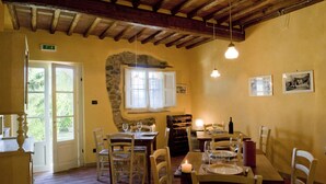 Uma sala de jantar com mesas e cadeiras de madeira, uma parede de pedra e teto de madeira.