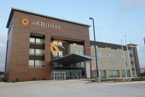 Um hotel La Quinta com design moderno, grandes janelas e um logotipo do sol em destaque.