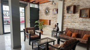 Um hall com parede de tijolos, um espelho grande, um sofá, duas poltronas e uma mesa de centro.