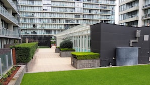 Um edifício moderno com vários andares, uma galeria coberta e áreas verdes bem cuidadas.