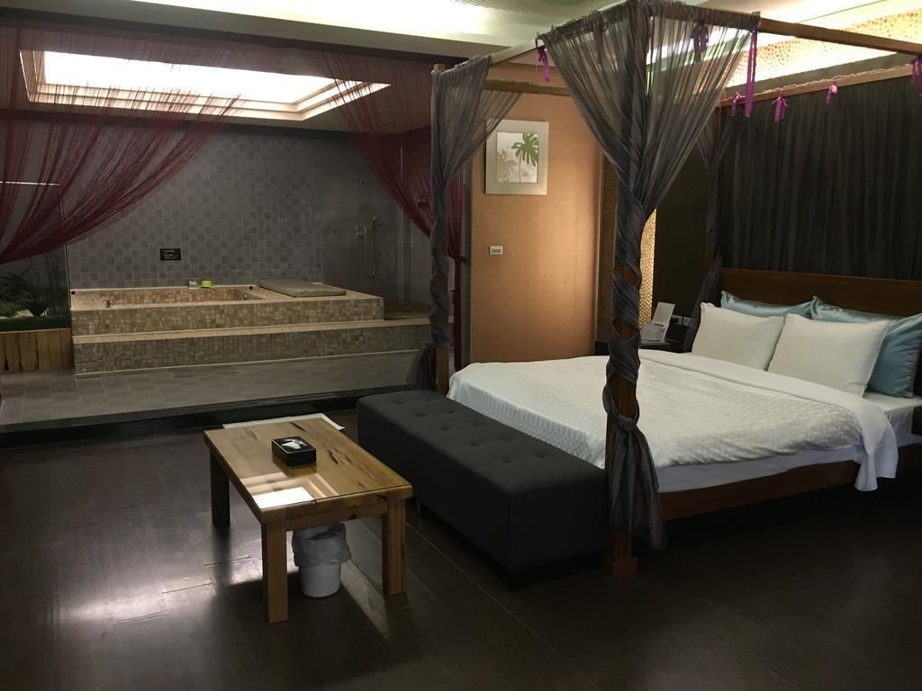 Quarto com cama de dossel, uma mesa pequena, um banquinho e uma banheira.