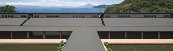 Um edifício moderno com telhado plano e várias janelas. Apresenta uma entrada longa e estreita com um deck de madeira em frente.