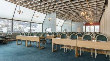 Uma sala de conferências com várias mesas e cadeiras, amplas janelas e um design moderno no teto.