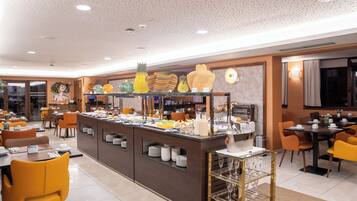 Uma área de buffet com diversos alimentos, um espaço de estar com cadeiras laranja e um balcão com um caixa registradora.