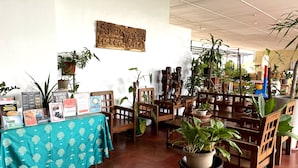 Quarto com móveis de madeira, plantas em vasos e cartazes informativos sobre uma mesa.