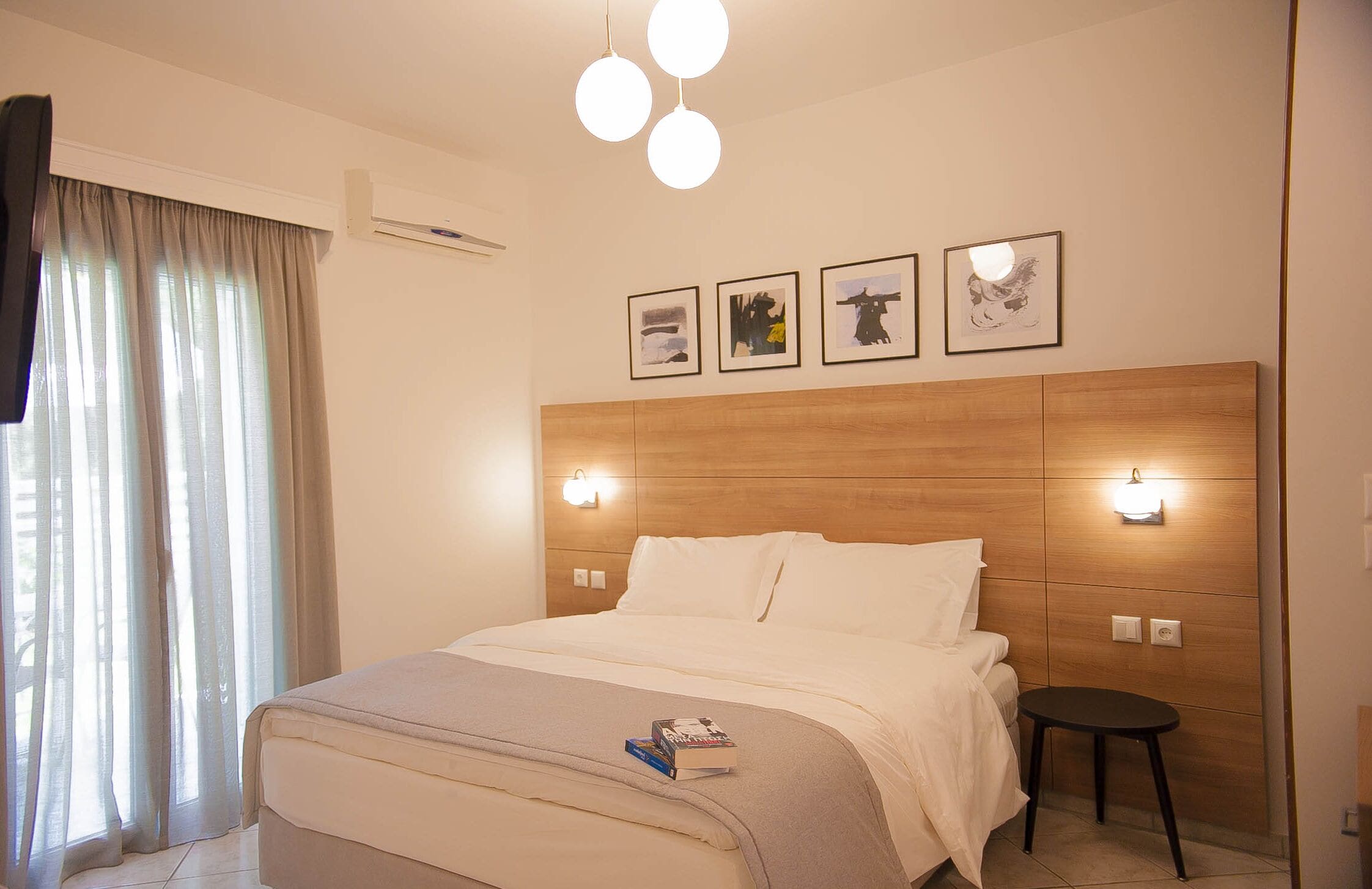 Quarto de hotel com uma cama grande, uma mesa de cabeceira e um aplique na parede.