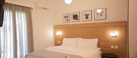 Quarto de hotel com uma cama grande, uma mesa de cabeceira e um aplique na parede.