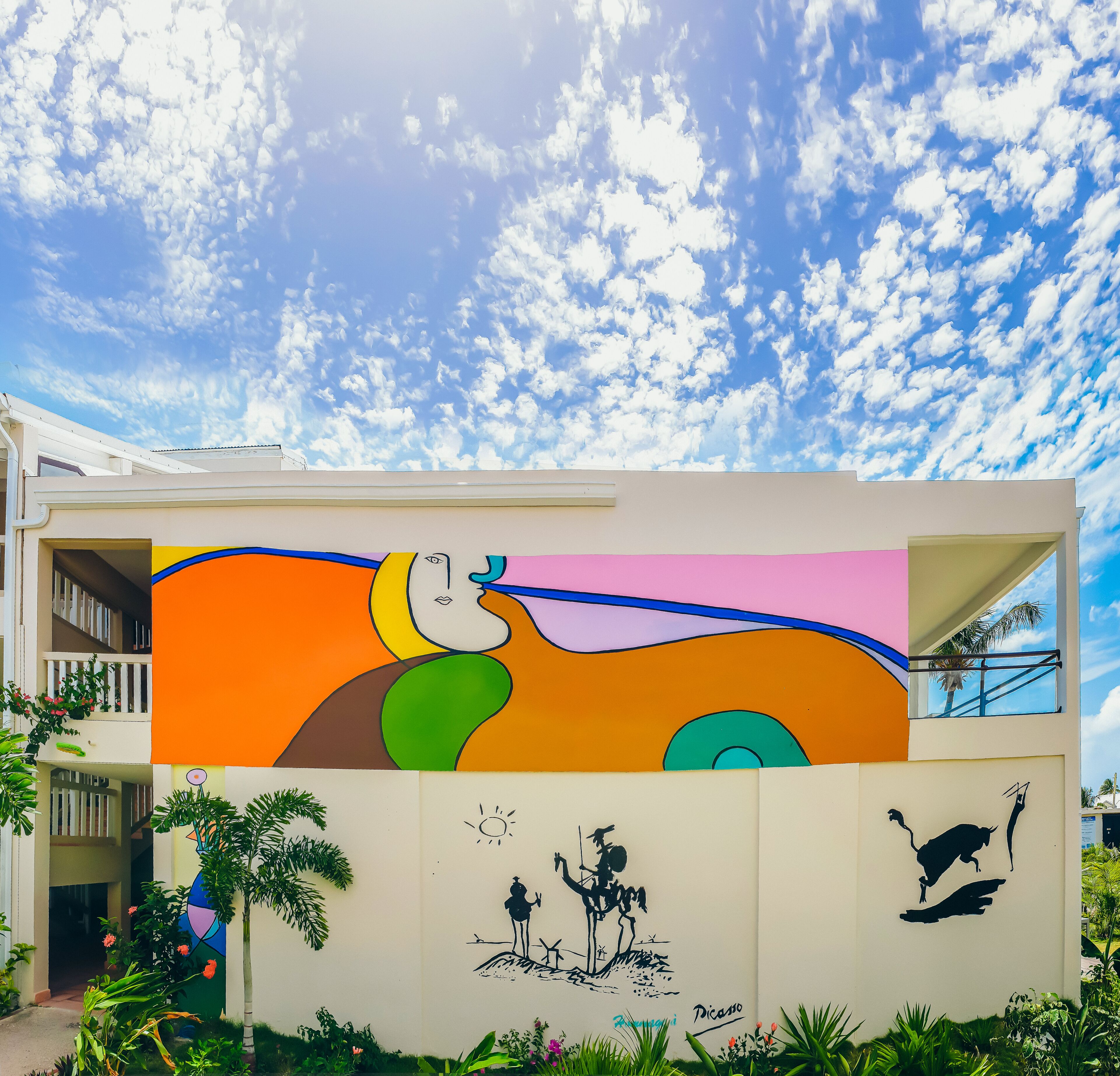 Um edifício com um mural colorido e uma varanda.