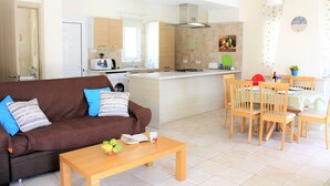 Uma sala de estar moderna com um sofá marrom, mesa de centro de madeira e uma área de jantar com cadeiras e mesa de madeira.