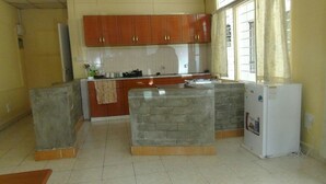 Cozinha com armários de madeira, ilha de pedra e geladeira branca.