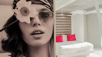 Quarto moderno com uma cama grande, roupa de cama branca e almofadas vermelhas.