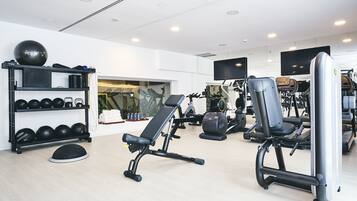 Academia moderna com diversos equipamentos de exercício, incluindo um banco de supino, halteres e bolas de ginástica.