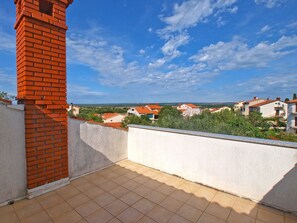 Varanda com chaminé de tijolos vermelhos, paredes brancas e chão de azulejos.