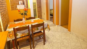 Uma área de refeições com uma mesa posta para quatro pessoas, um vaso com flores e uma parede de tijolos.