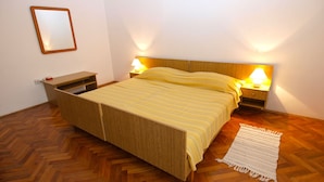 Quarto bem arrumado com uma cama de madeira, mesas de cabeceira e um espelho na parede.