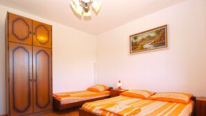 Quarto com duas camas, um guarda-roupa de madeira, um quadro na parede e chão de madeira.