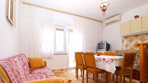 Uma sala de estar aconchegante com um sofá, uma mesa de jantar com cadeiras, uma televisão e um armário.