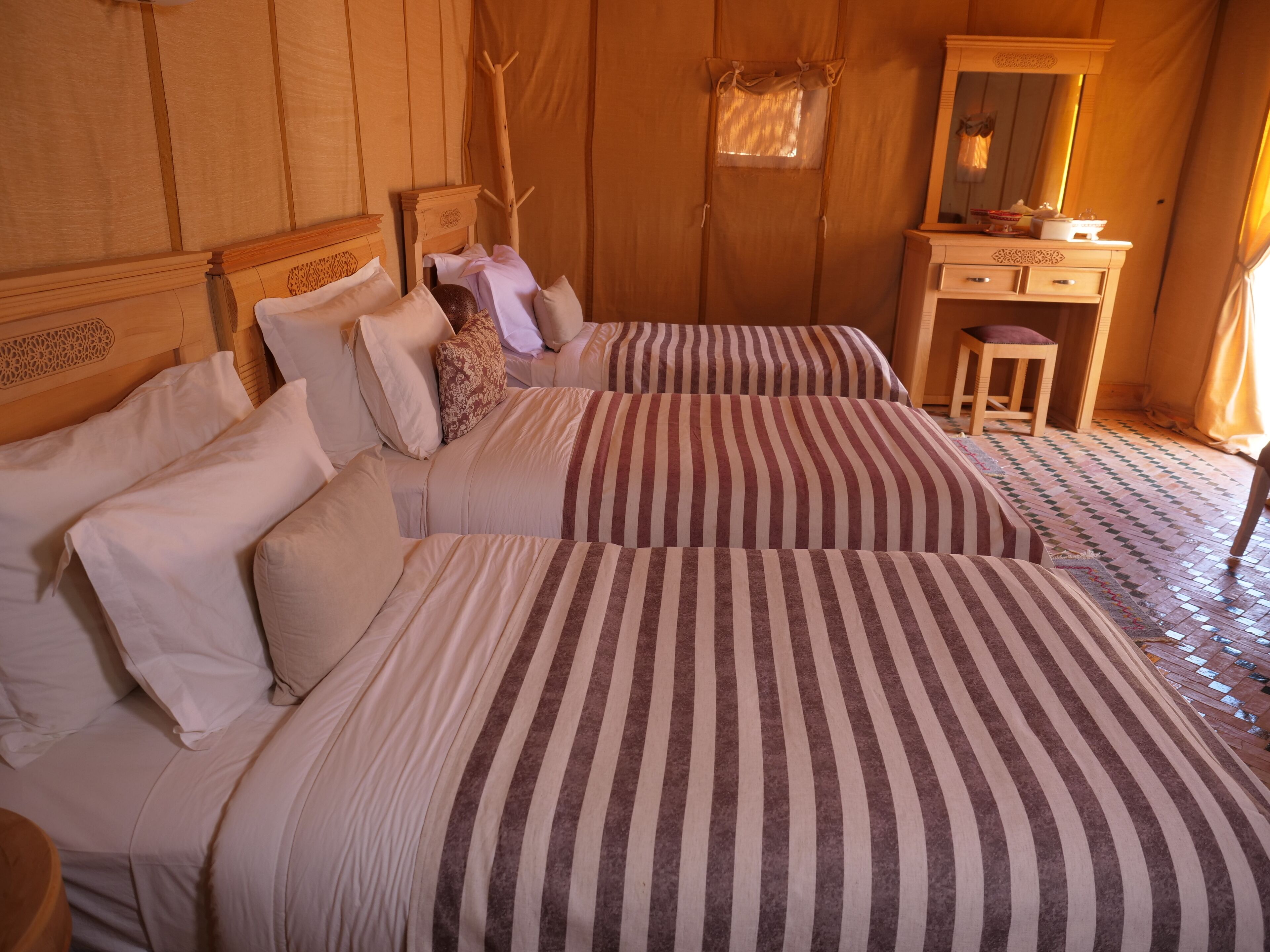 Quarto com duas camas, cômoda de madeira, espelho e janela.