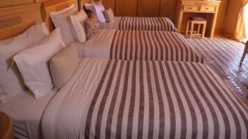 Quarto com duas camas, cômoda de madeira, espelho e janela.