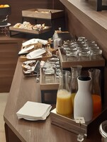 Buffet de café da manhã com diversos pães, bolos e bebidas.