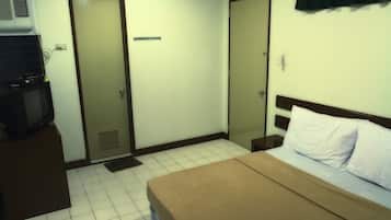 Quarto de hotel com uma cama, uma televisão sobre um suporte e duas portas.