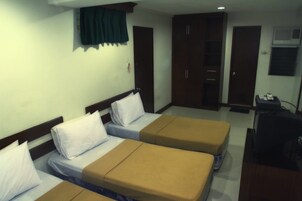 Quarto de hotel com duas camas de solteiro, um guarda-roupa, uma escrivaninha com computador e um aparelho de ar condicionado.