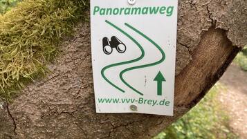 Uma placa numa árvore com o texto 'Panoramaweg' e um endereço de site.