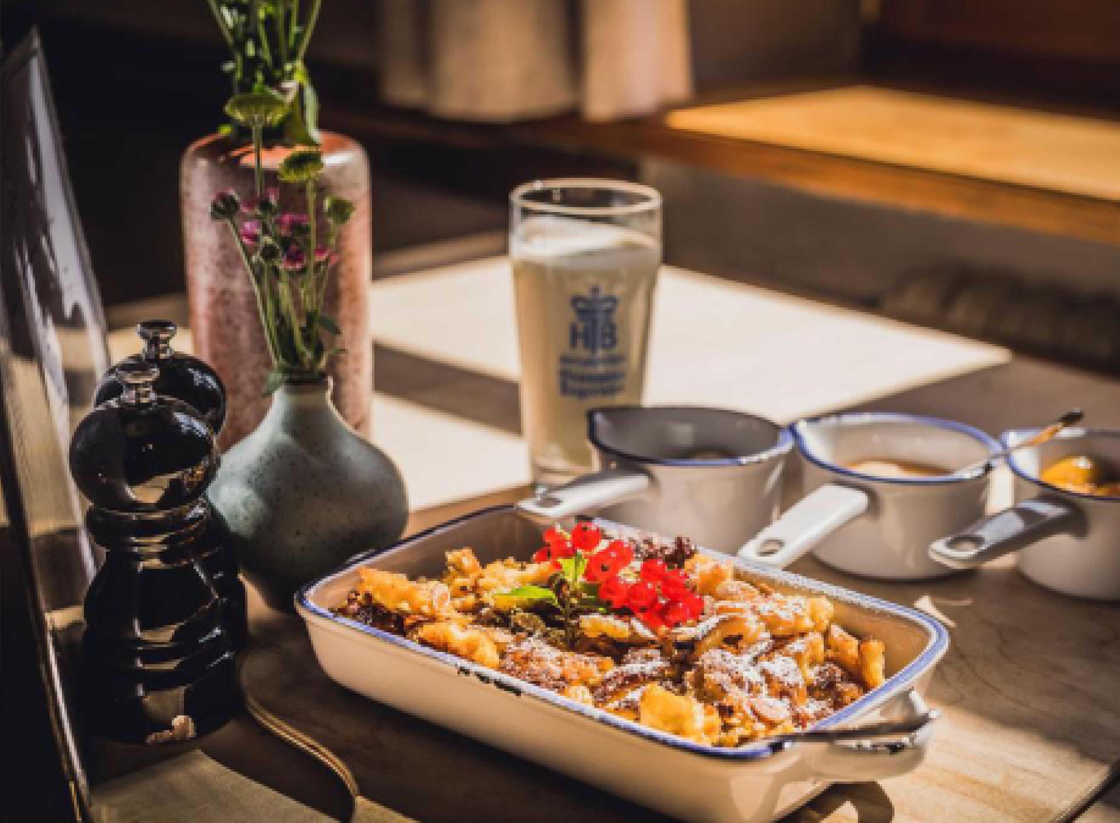 Uma mesa de jantar com um prato de comida, um vaso de flores, um saleiro e um copo de água.