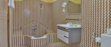Casa de banho com papel de parede estampado, chuveiro, lavatório e sanita.