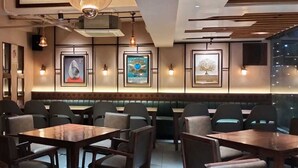 Um interior de restaurante com cabines, mesas e obras de arte emolduradas nas paredes.