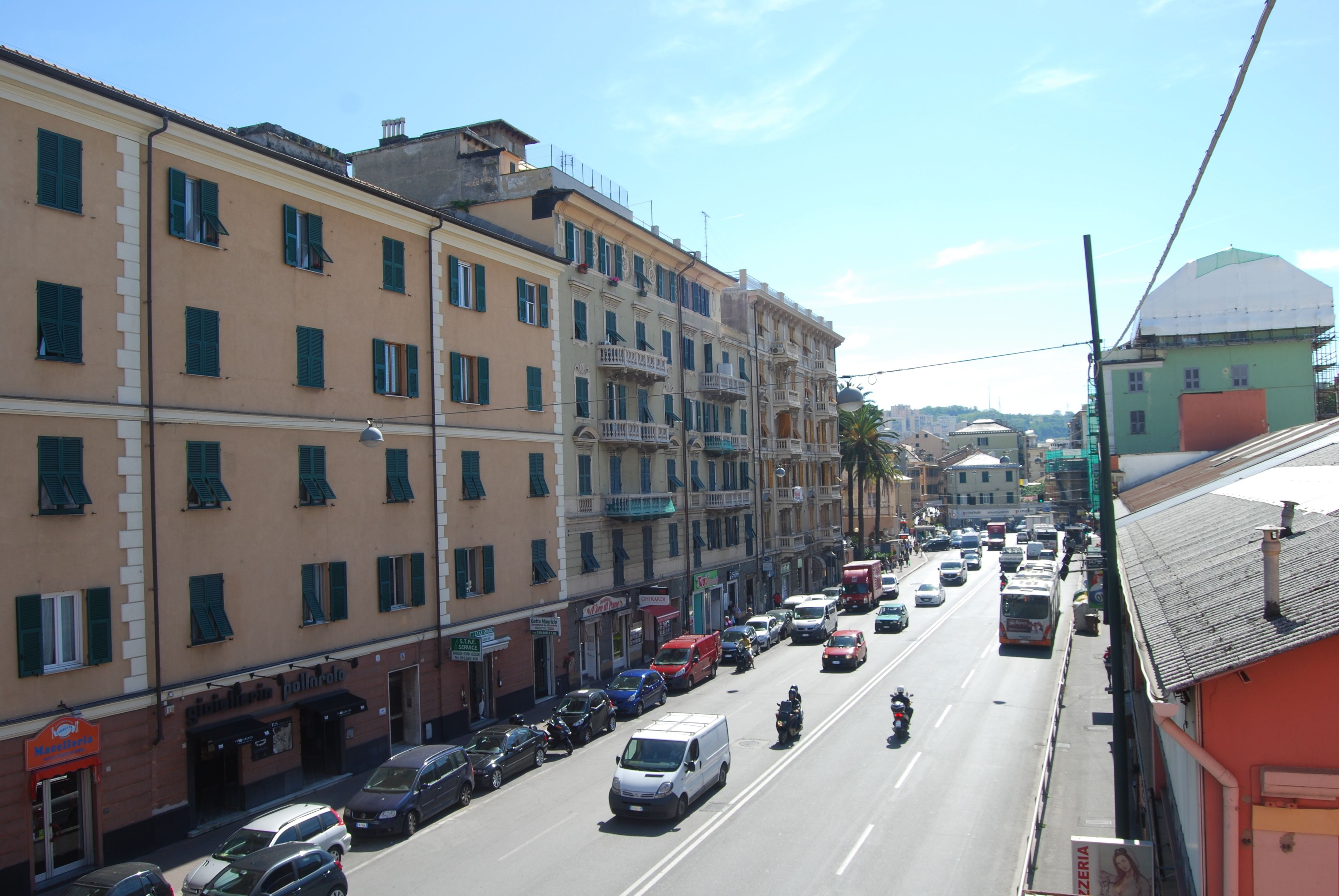 Vista da rua com edifícios altos, carros estacionados e um ônibus.