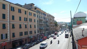 Vista da rua com edifícios altos, carros estacionados e um ônibus.