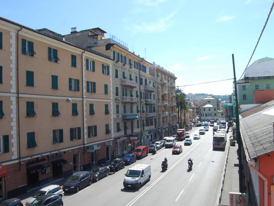 Vista da rua com edifícios altos, carros estacionados e um ônibus.