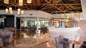 Um hall amplo com piso de mármore, balcão de recepção e área de bar com garrafas.