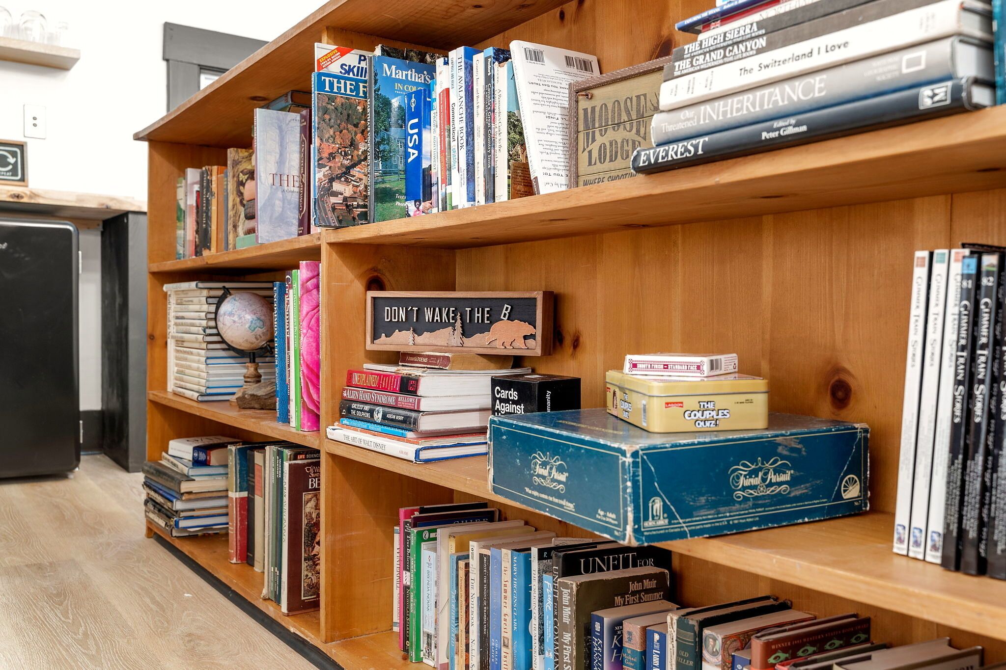 Uma estante com diversos livros, incluindo guias de viagem e romances.