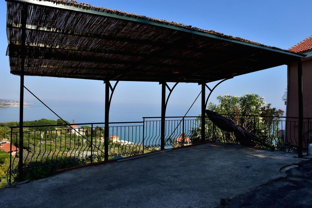 Uma área externa coberta com vista para o mar, cerca de metal e um edifício com telhado vermelho.