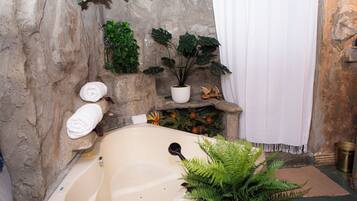 Casa de banho com banheira, porta-toalhas, uma planta em vaso e cortina de chuveiro.