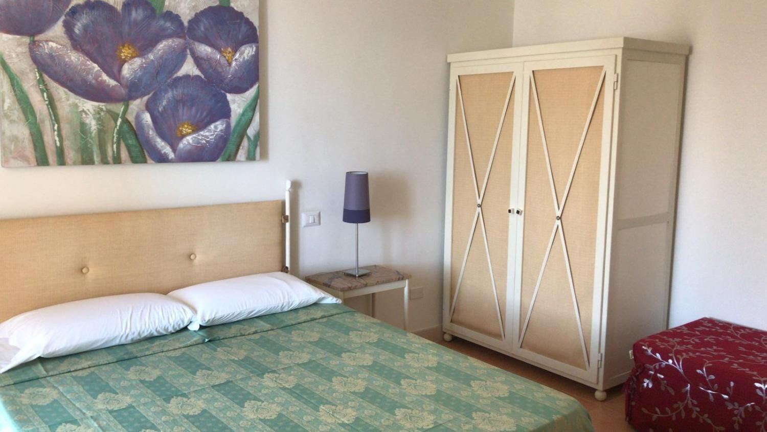 Quarto com cama, guarda-roupa, mesa de cabeceira e abajur.