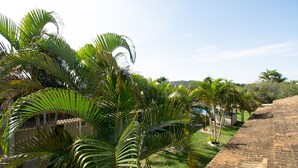 Um pátio com palmeiras, um muro de tijolos e vista para uma paisagem montanhosa.