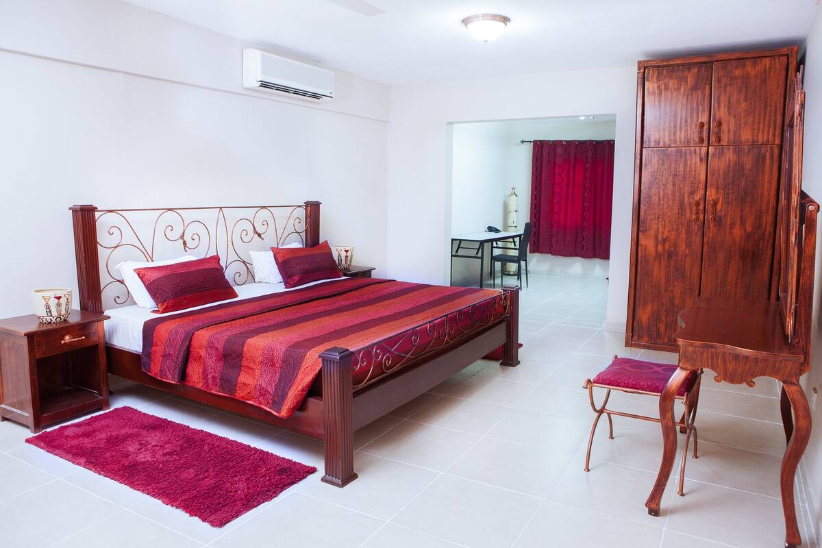 Quarto com cama, mesa de cabeceira e guarda-roupa de madeira.