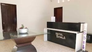 Uma receção com uma placa a indicar "HOTEL TONALÁ" e uma planta em vaso no lado esquerdo.