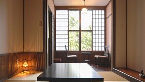 Um quarto japonês tradicional com tatames, uma mesa baixa e portas deslizantes.