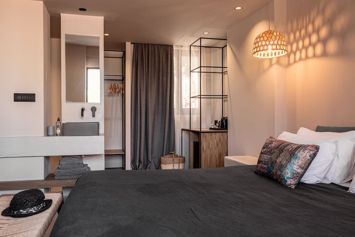Quarto moderno com uma cama grande, uma mesa de cabeceira, um espelho, um guarda-roupa e uma luminária suspensa.